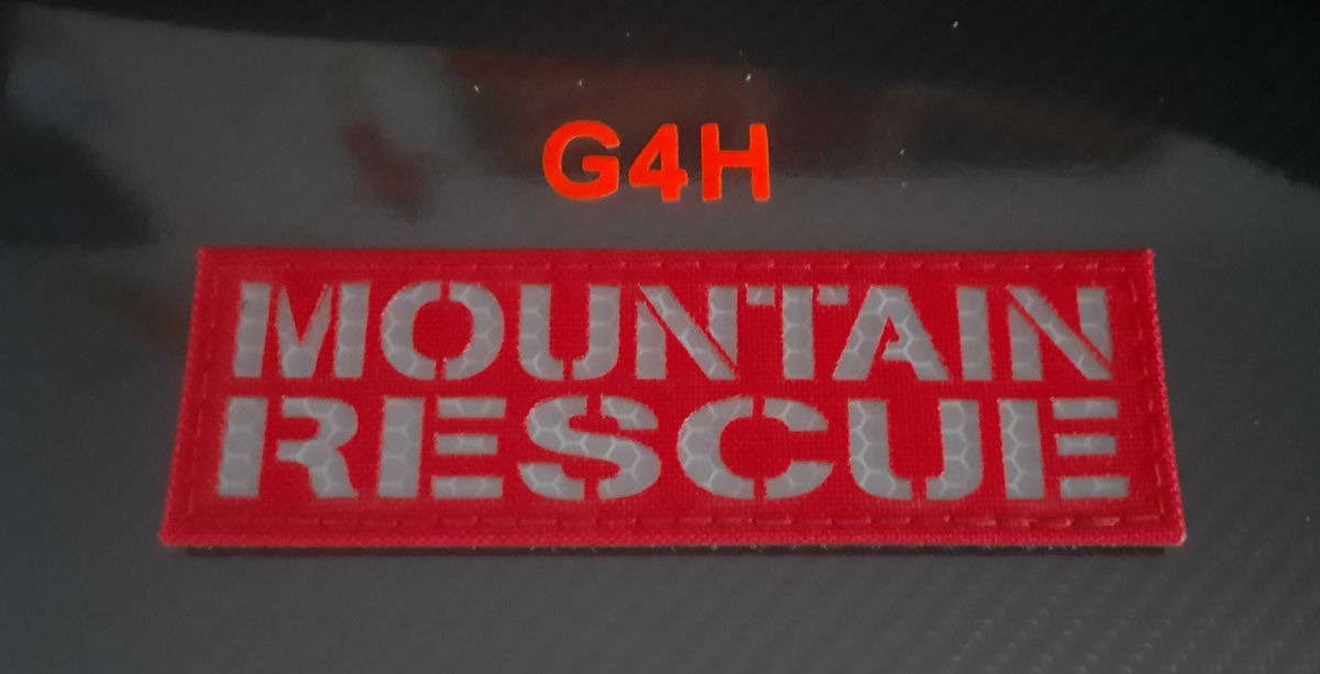 MOUNTAIN RESCUE laser cut velcro patch, red with silver reflective text.